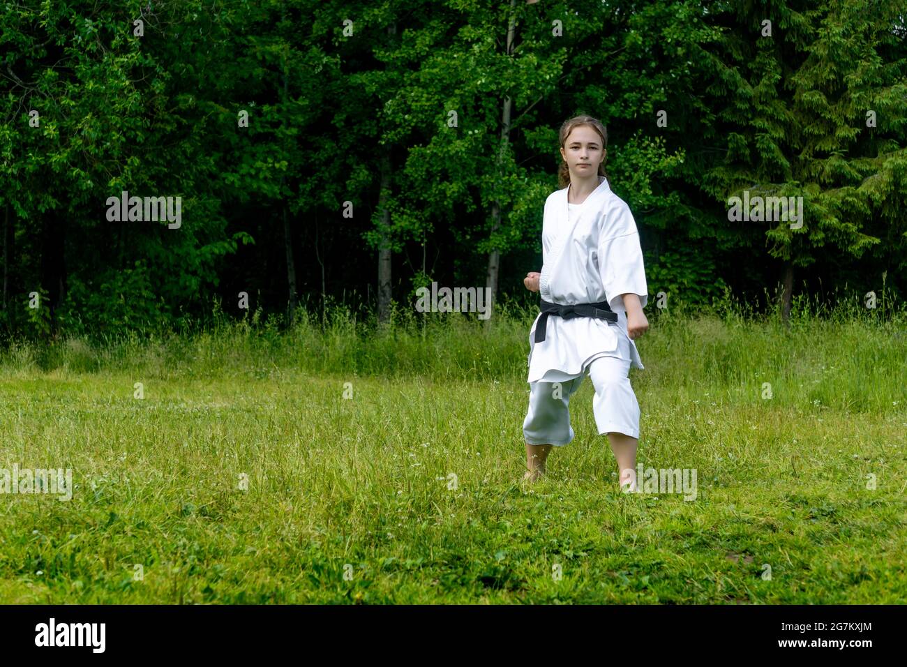 teenage girl practicing karate kata outdoors, performs the gedan-barai ...