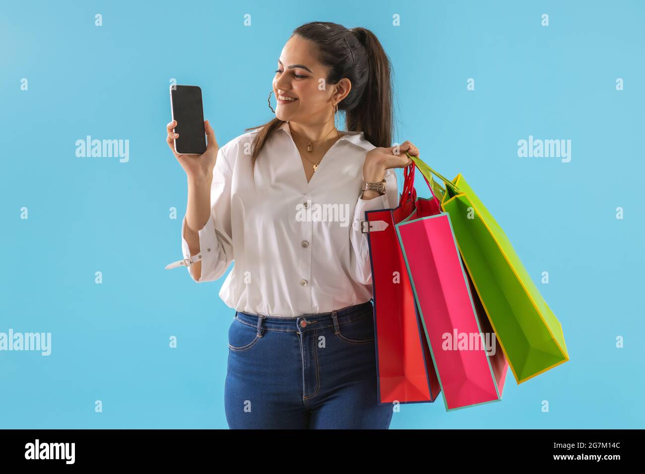 A young woman standing with Carry bags showing her phone Stock Photo ...