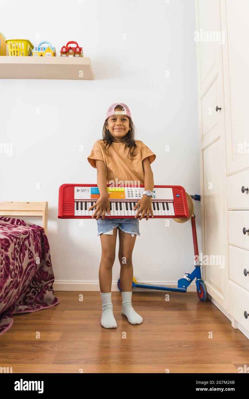 Young Hispanic girl holding piano at home Stock Photo - Alamy
