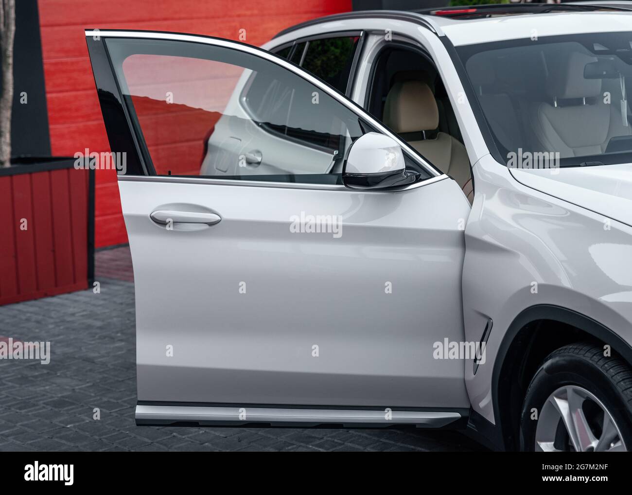 The front passenger door is open close up. White color modern SUV car ...