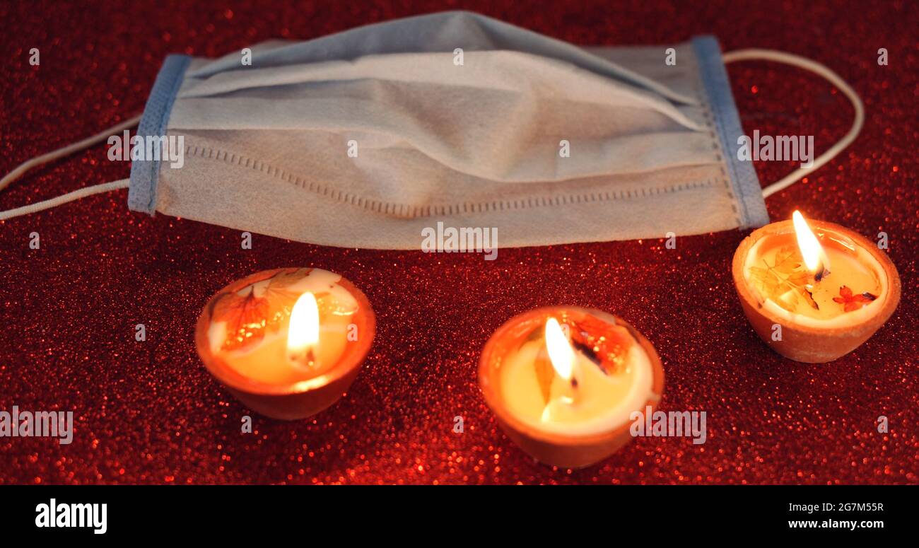 Candles and a protective face mask on the red surface; Diwali festival ...