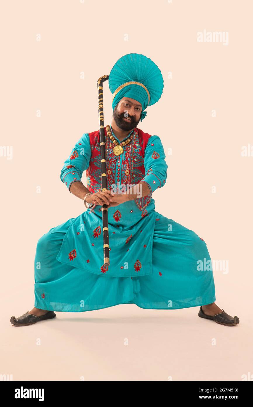 A Bhangra Dancer bending over while holding the Khunda Stock Photo - Alamy