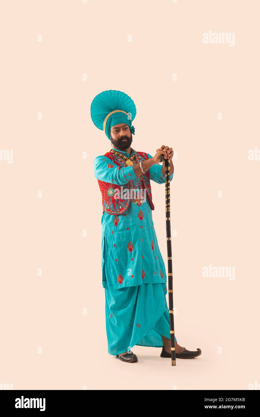 A Bhangra dancer with a grave expression standing with the Khunda Stock ...