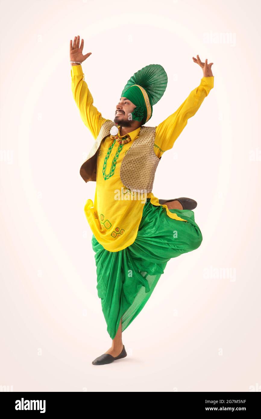 A Bhangra Dancer facing left performing a dance step with hands and a ...