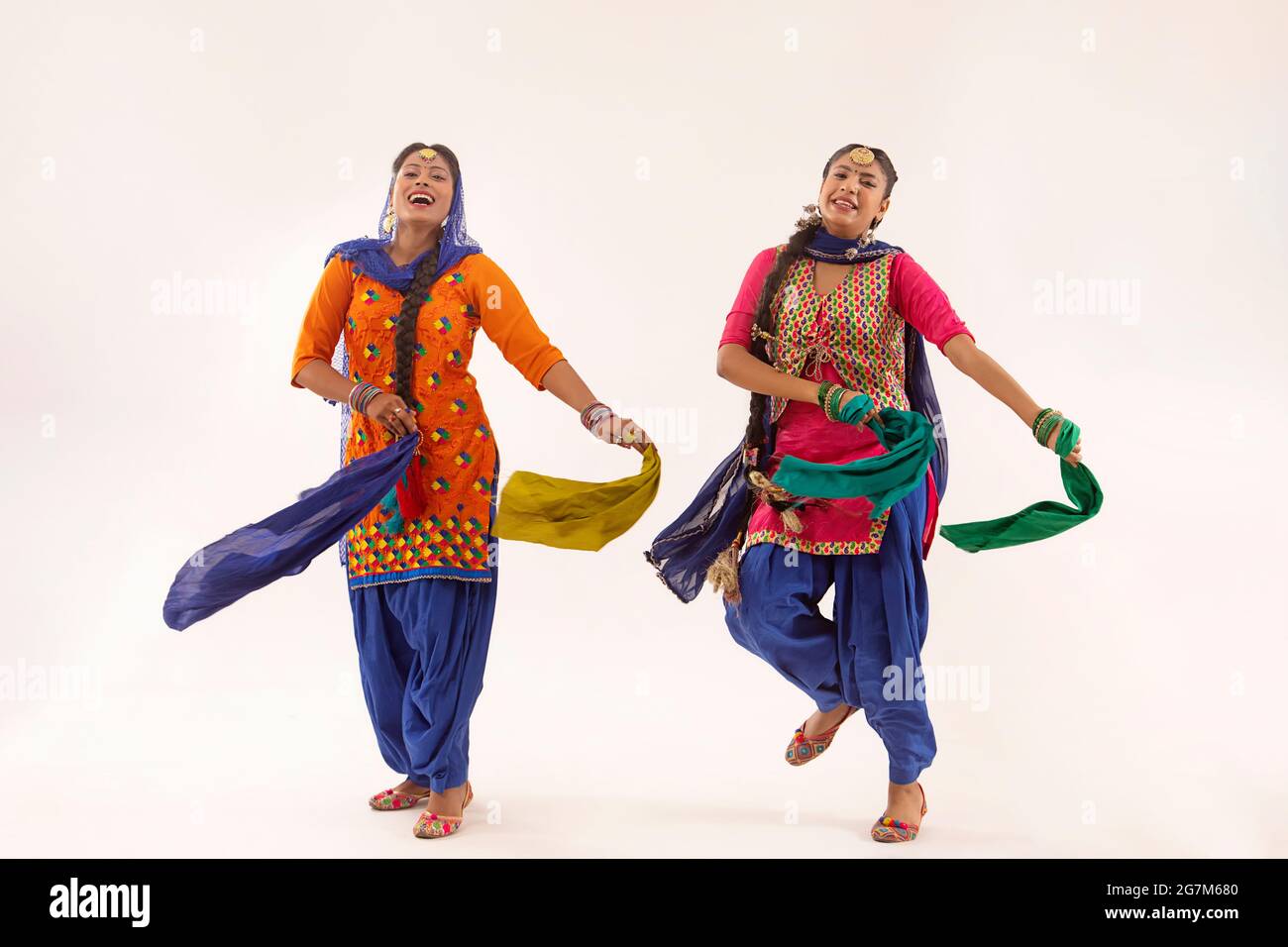 Two Giddha dancers depicting a dance step with colourful cloth in their ...