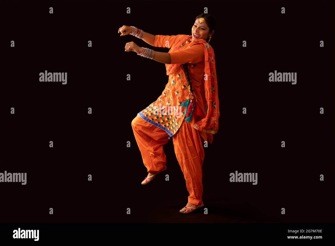 A woman in Giddha costume depicting a dance step with hand gestures ...
