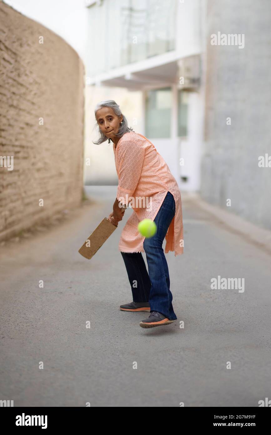 An old woman playing cricket about to hit a ball Stock Photo - Alamy