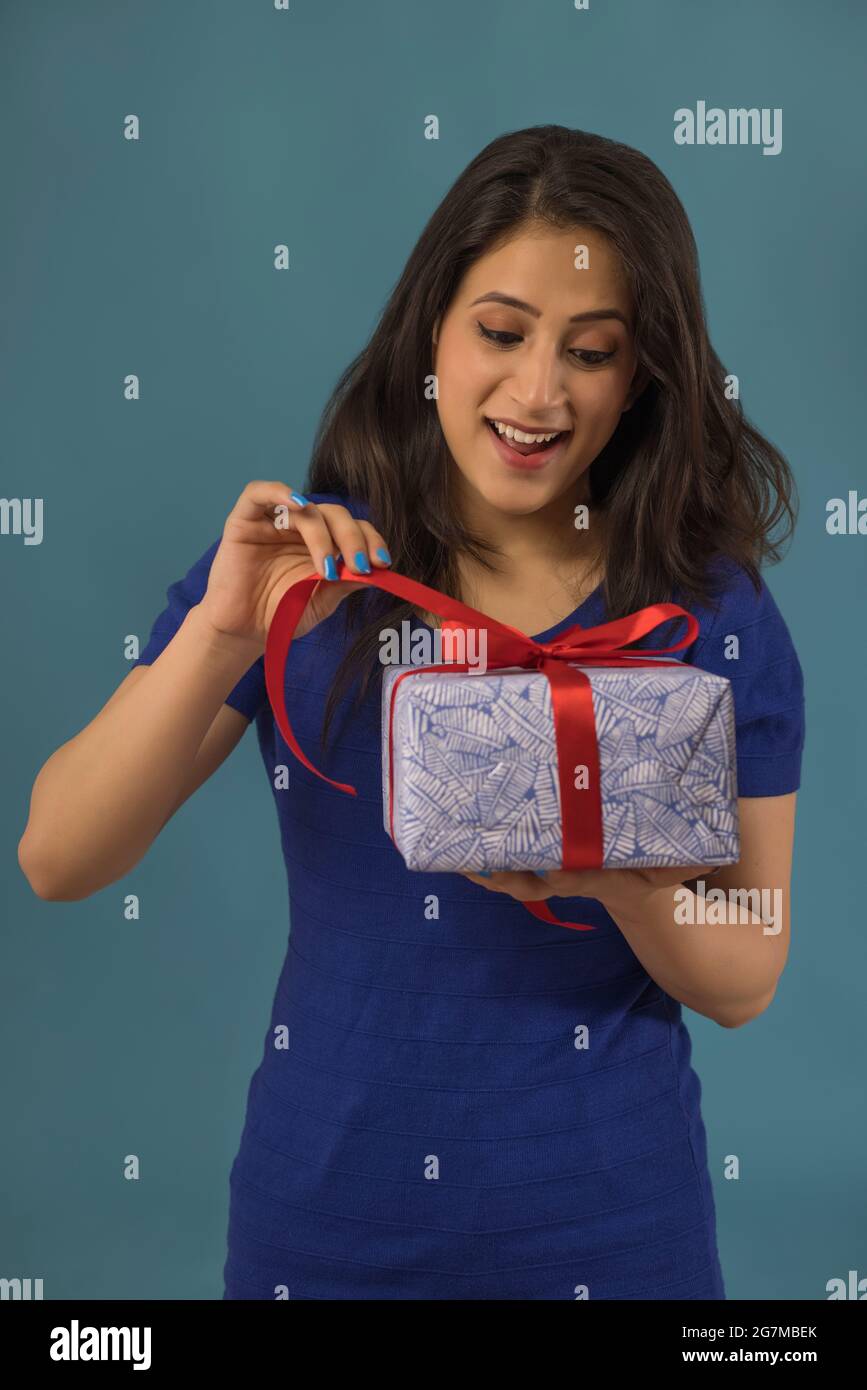Portrait of a young woman opening a gift Stock Photo - Alamy