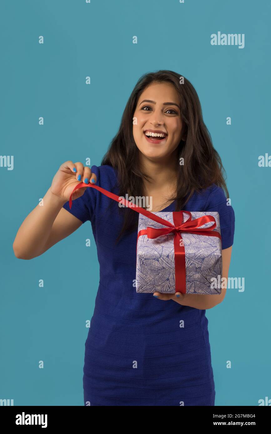 Portrait of a young woman opening a gift Stock Photo - Alamy