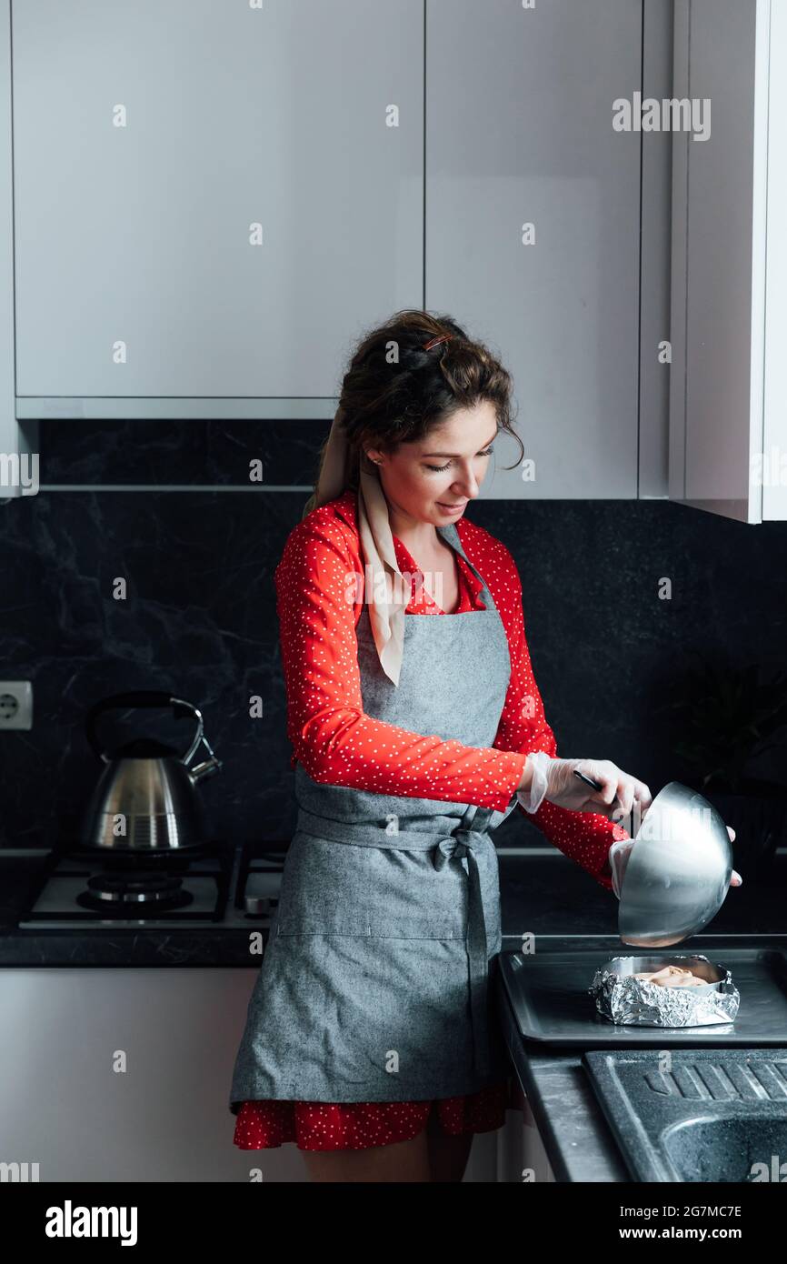 beautiful woman housewife in a red dress prepares sweet desserts in the ...