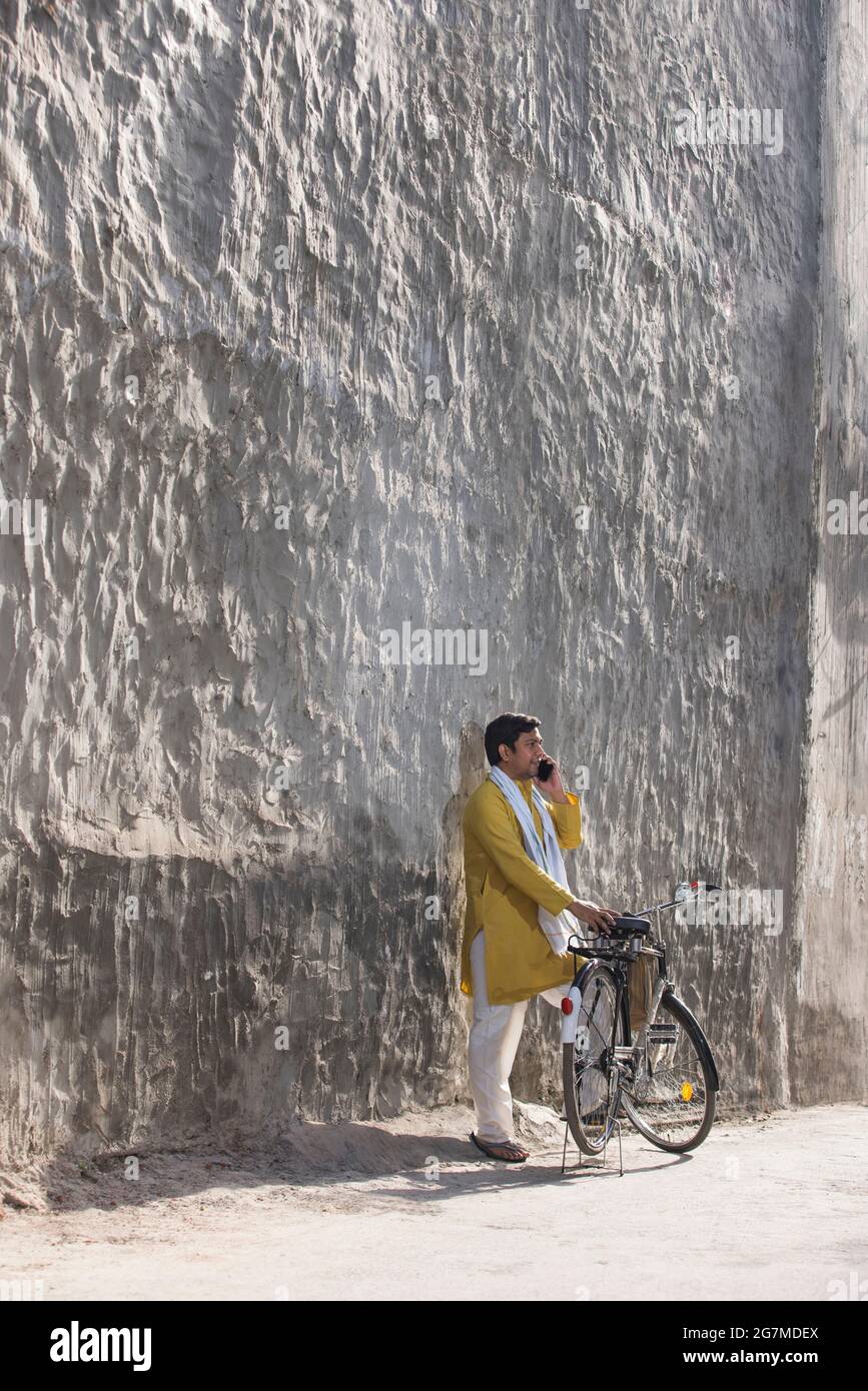 A VILLAGER STANDING AND TALKING WHILE STANDING WITH CYCLE Stock Photo ...