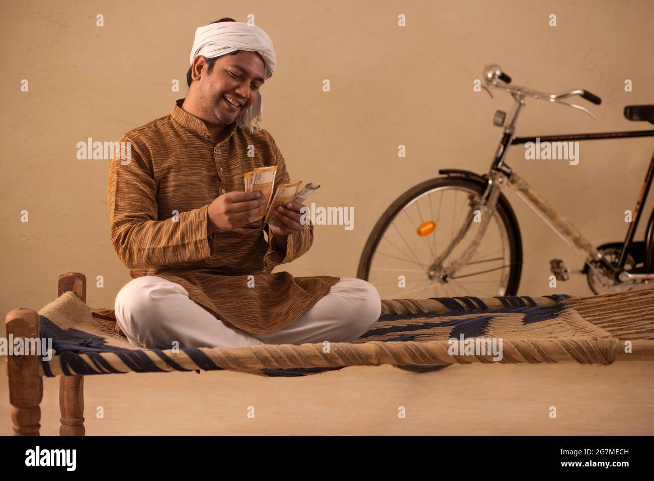 A RURAL MAN SITTING ON A COT AND HAPPILY COUNTING MONEY Stock Photo - Alamy
