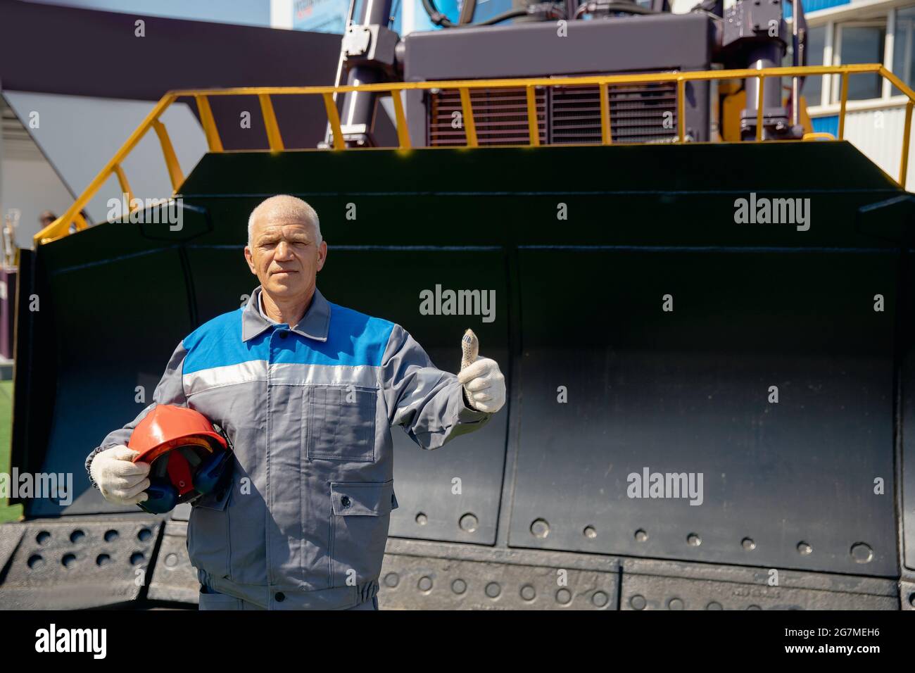 Bulldozer driver coal mine in uniform with helmet and headphones ...
