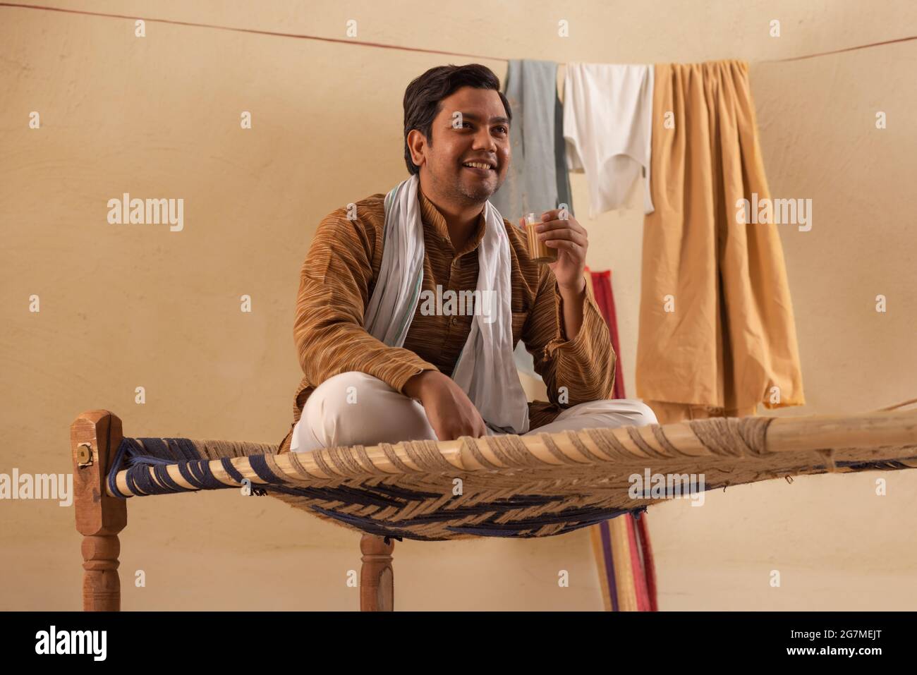 A RURAL MAN SITTING ON A COT HOLDING A GLASS OF TEA Stock Photo - Alamy