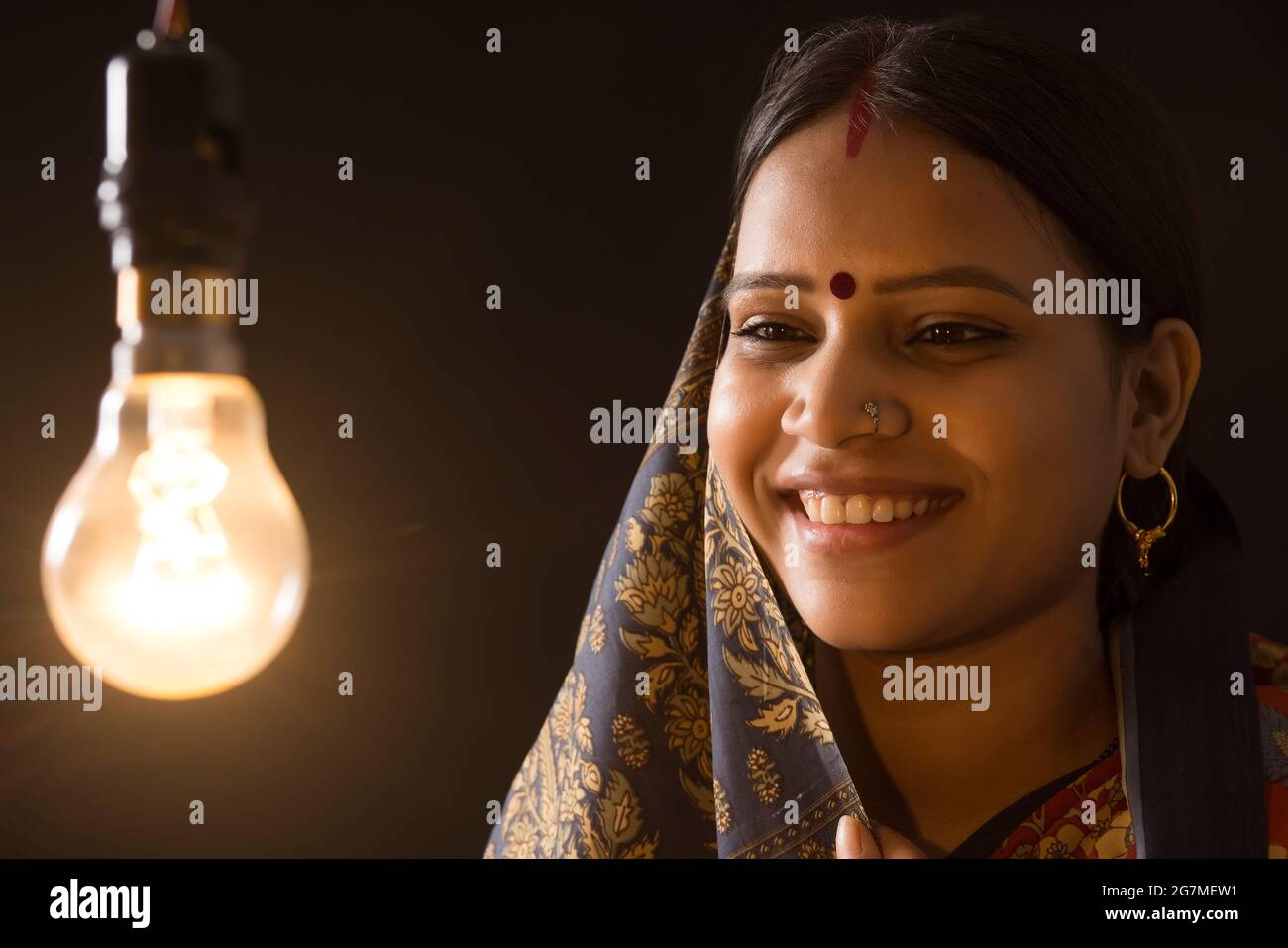 A CHEERFUL RURAL WOMAN LOOKING AT A LIGHT BULB AND SMILING Stock Photo ...