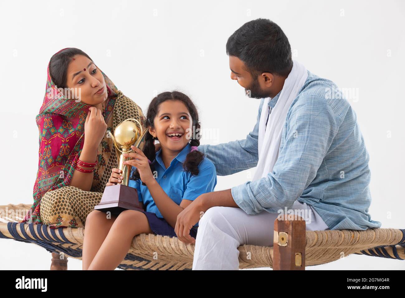 PORTRAIT OF A RURAL SCHOOLGIRL SHOWING HAPPILY HER TROPHY TO PARENTS ...