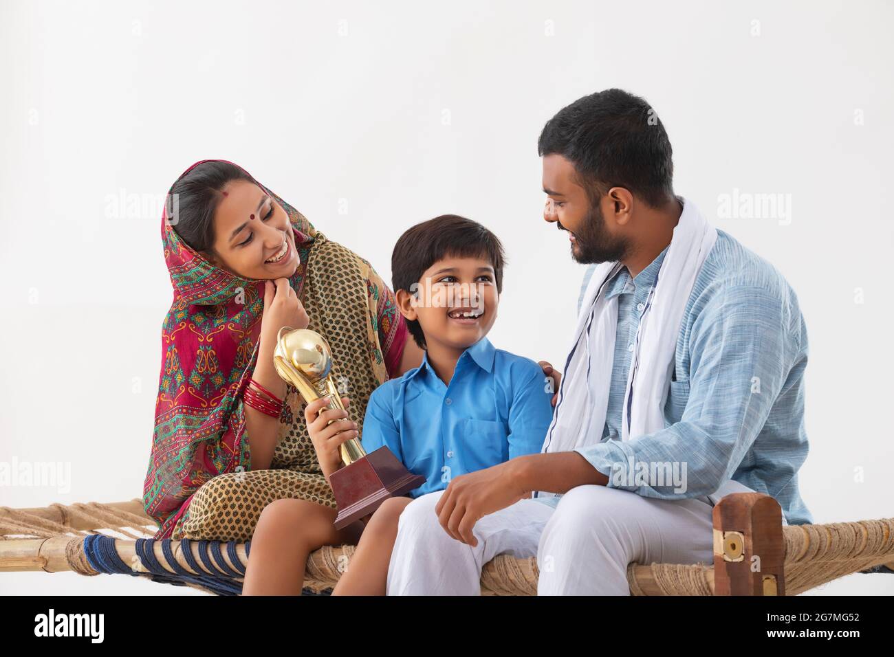 PORTRAIT OF A RURAL BOY SHOWING HAPPILY HIS TROPHY TO PARENTS Stock ...