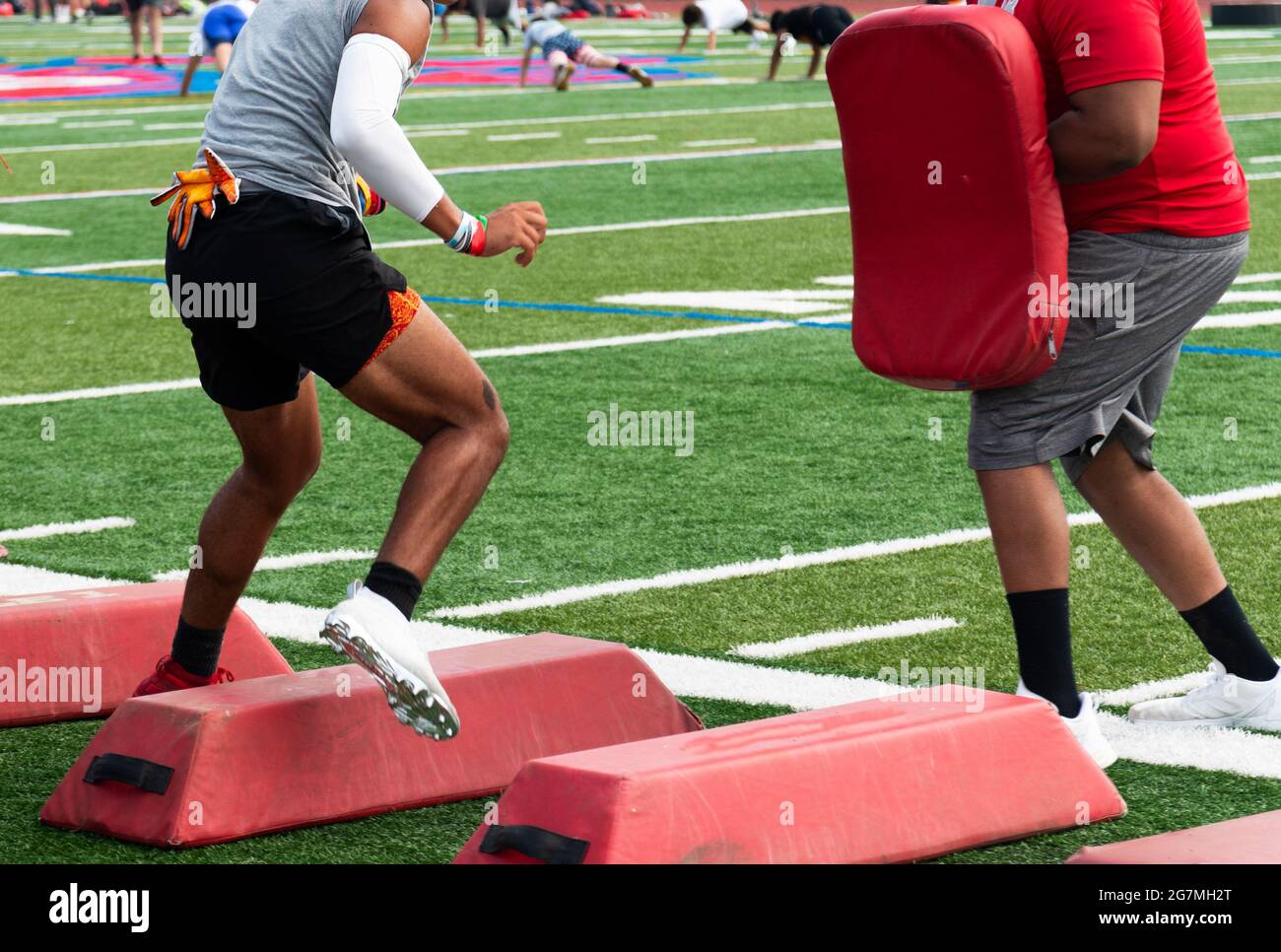 Football player running sideways over red barriers while taking a hit ...