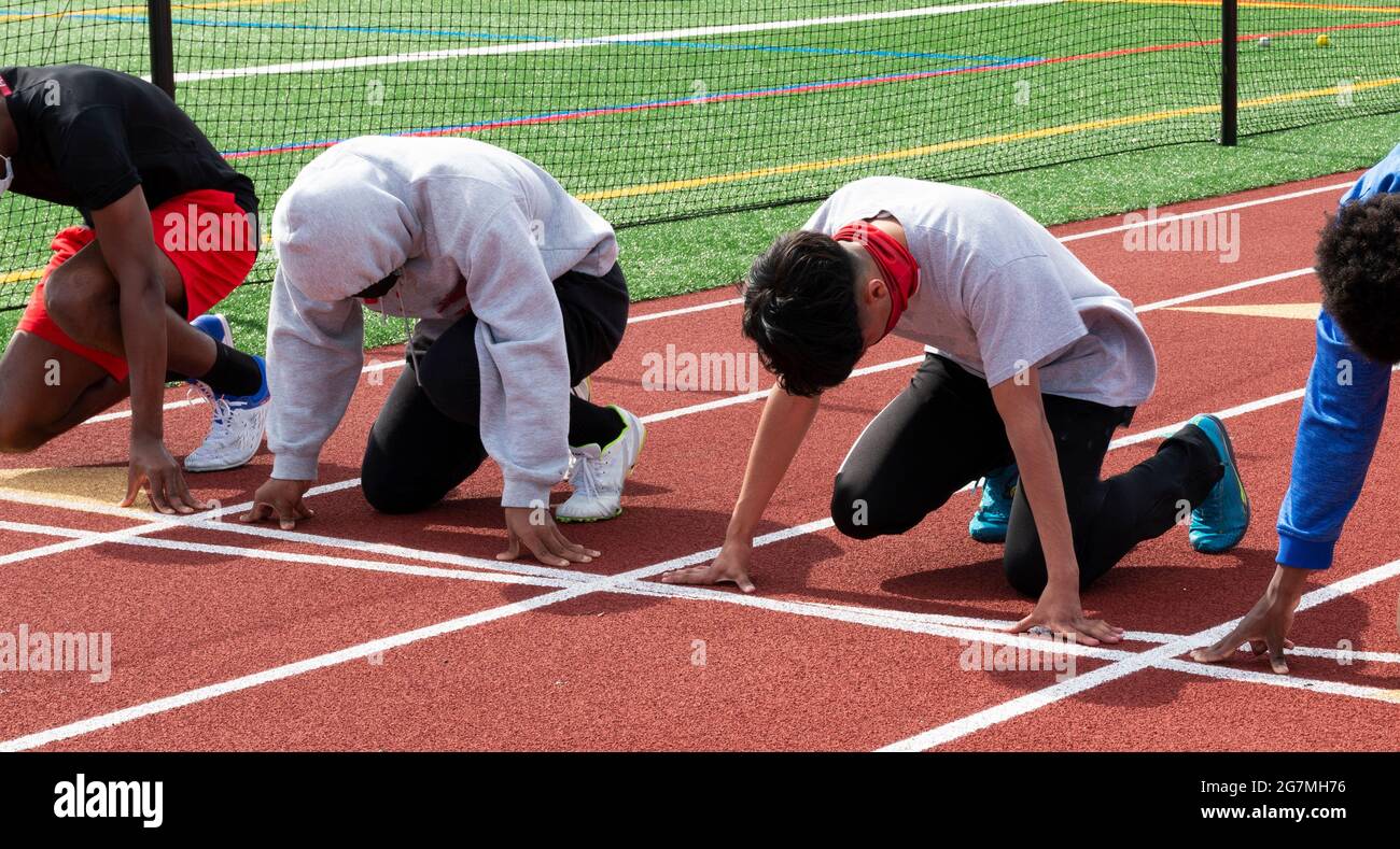 Four high school track runners on the starting line ready to compete in ...