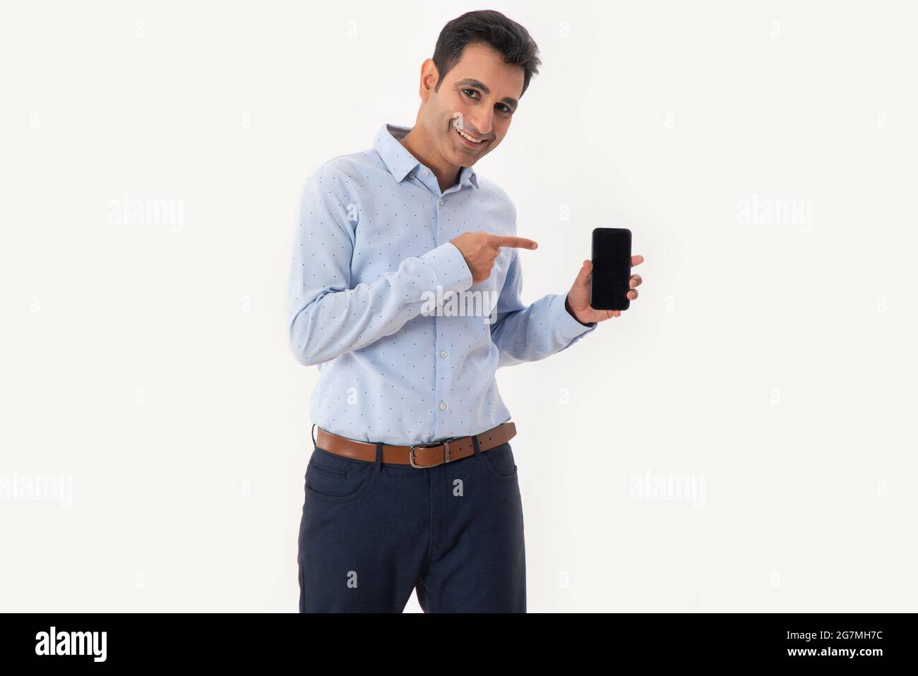 A CORPORATE MAN STANDING AND POINTING TOWARDS MOBILE PHONE IN HAND ...