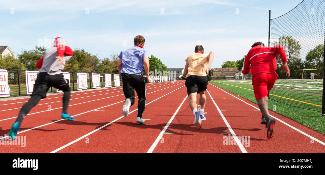 Rear view of high school boys sprinting down the track in lanes racing ...