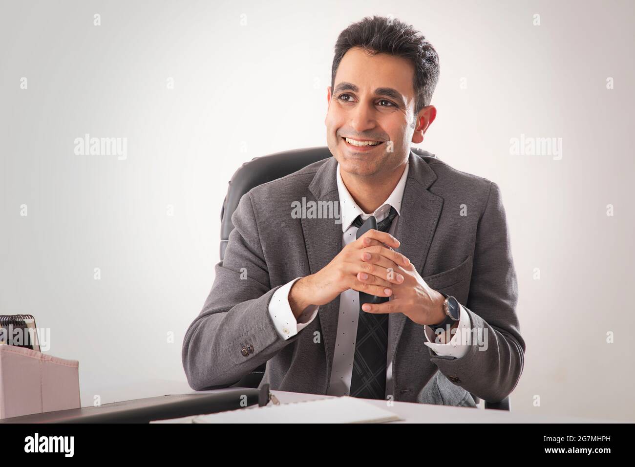 PORTRAIT OF A CORPORATE LEADER SITTING IN OFFICE AND HAPPILY THINKING ...