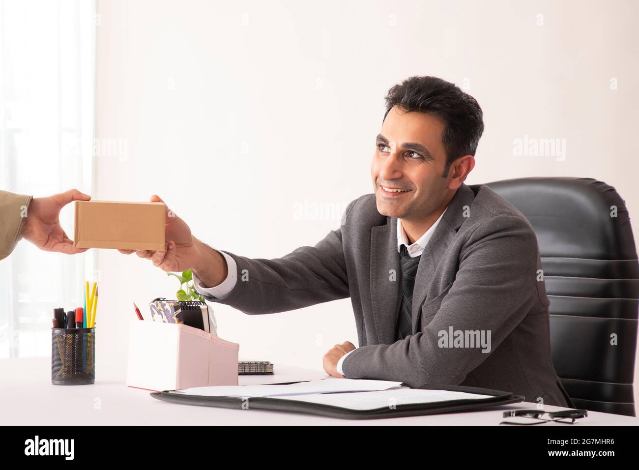 A CORPORATE PROFESSIONAL HAPPILY SITTING AND HANDING OVER A BOX Stock ...