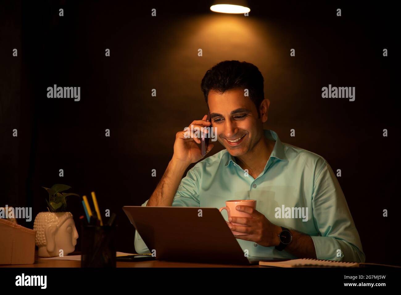 A HAPPY CORPORATE PROFESSIONAL ATTENDING A PHONE CALL WHILE WORKING ...