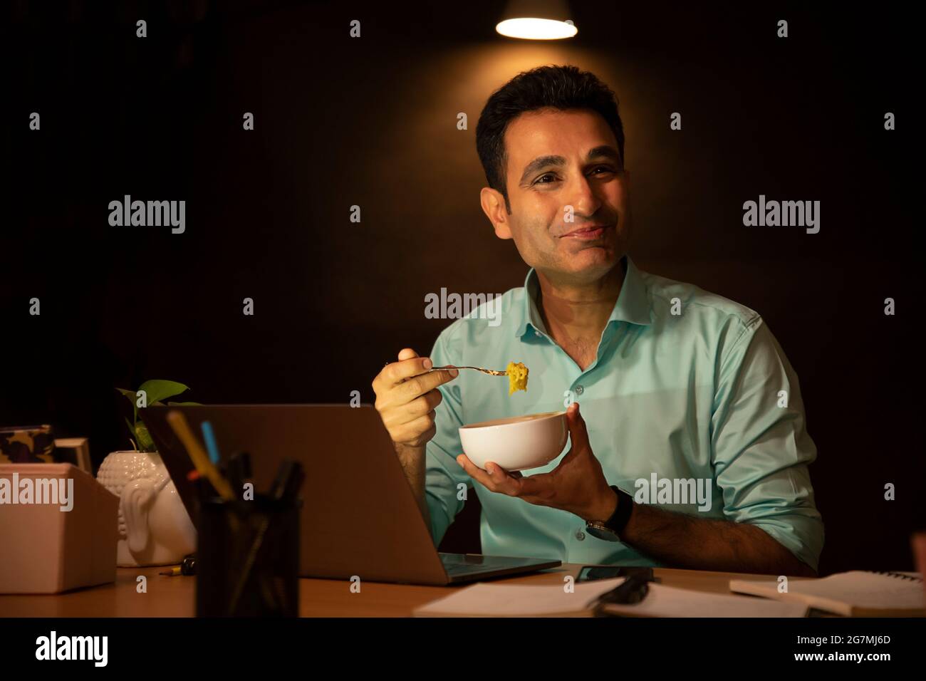 A CORPORATE PROFESSIONAL HAPPILY EATING MAGGI WHILE WORKING LATE AT ...