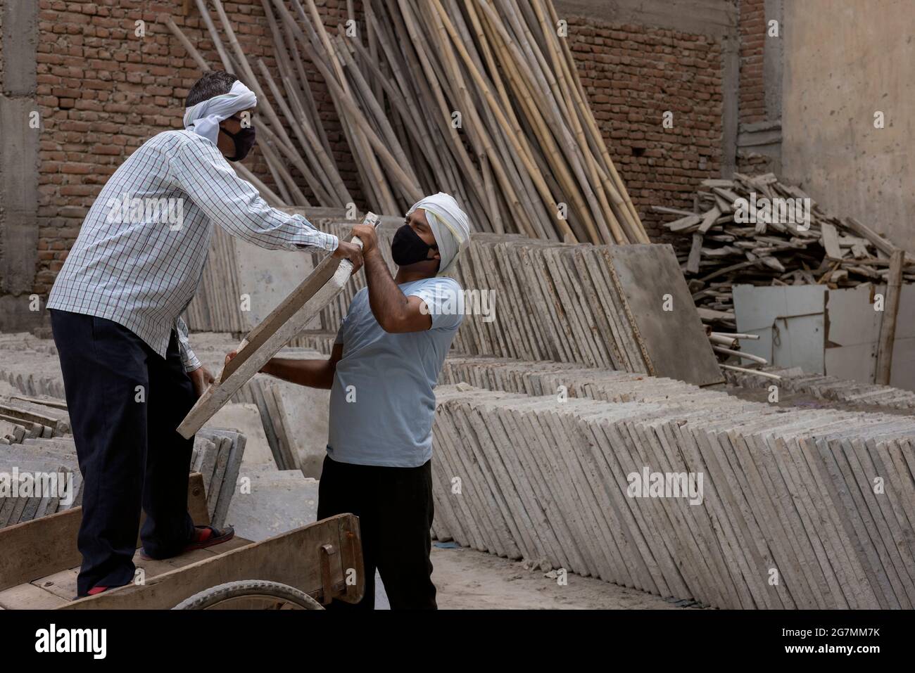 TWO WORKERS WEARING FACE MASKS HOLDING BLOCK OF TILE Stock Photo - Alamy
