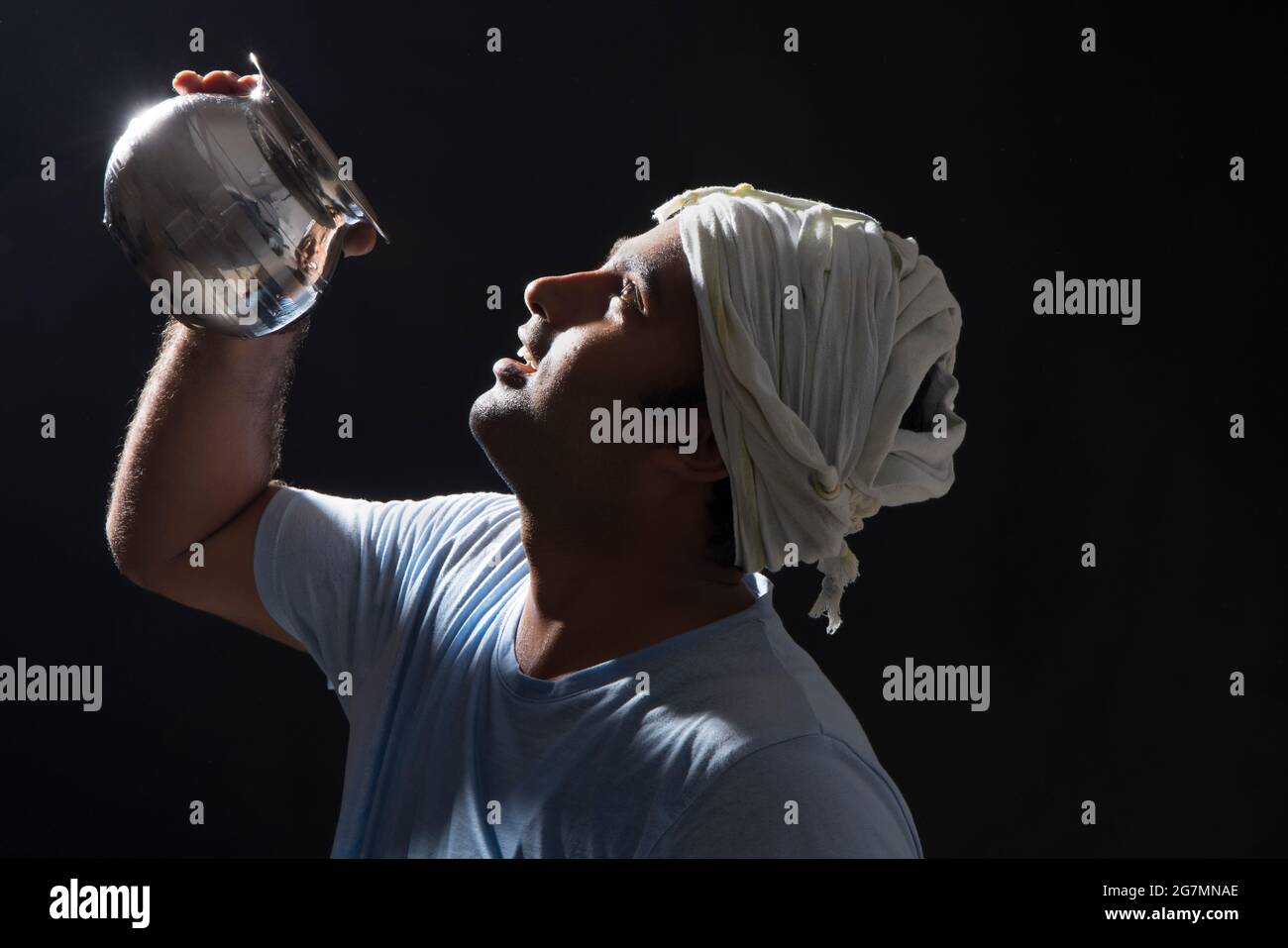 A LABOURER DRINKING WATER FROM A STEEL POT AT NIGHT Stock Photo - Alamy