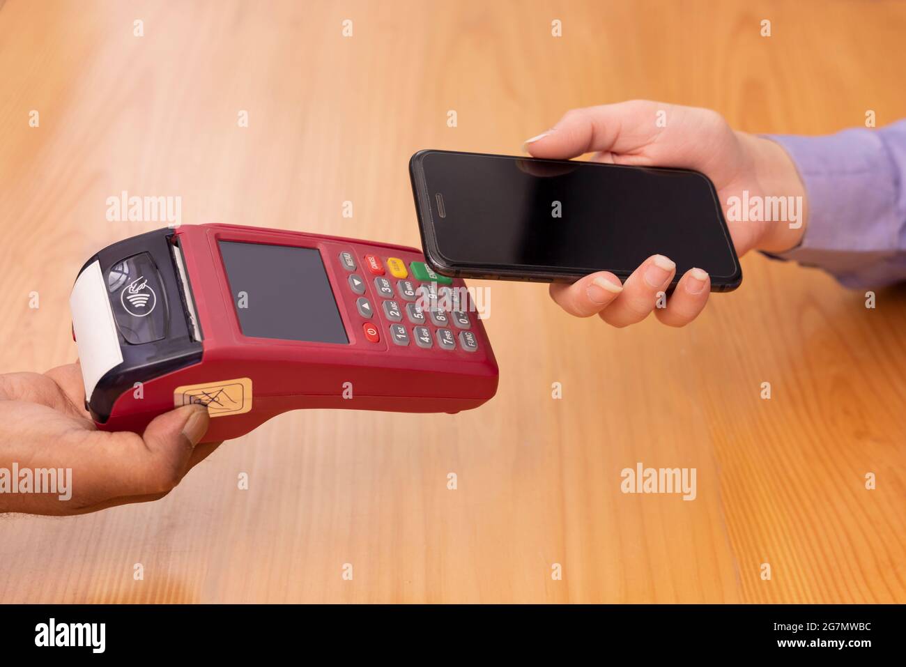 Two hands holding a swipe machine and mobile phone Stock Photo - Alamy