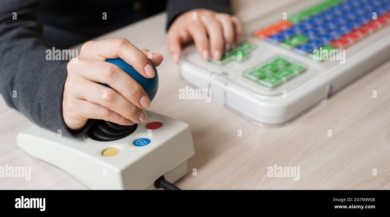 An unrecognizable woman with cerebral palsy is typing on the keyboard ...