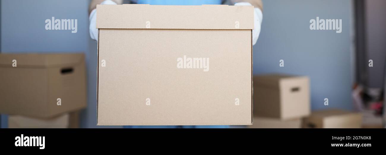 Male courier is holding large cardboard box Stock Photo - Alamy