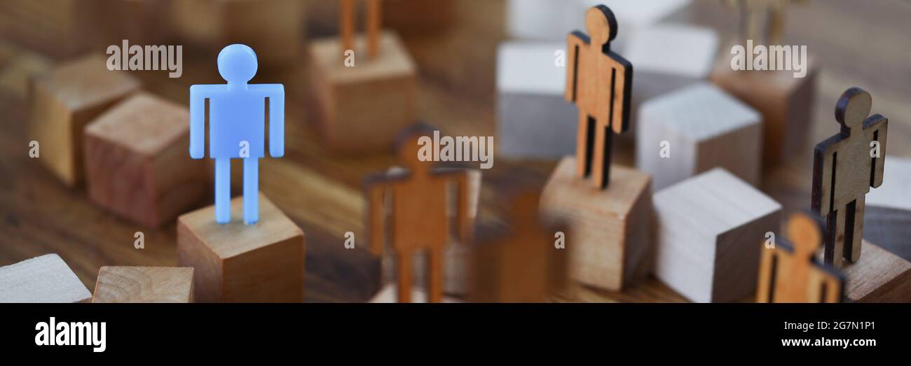 Wooden men on wooden cubes of brown color, one of them is blue Stock ...