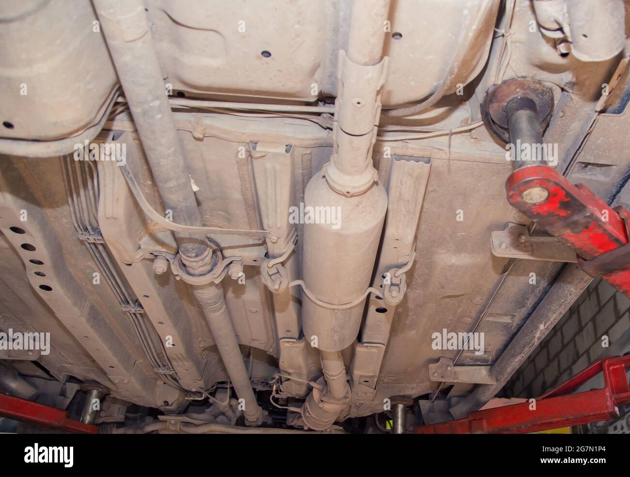 Bottom view of the underbody of an old car on a lift. In the garage, a ...
