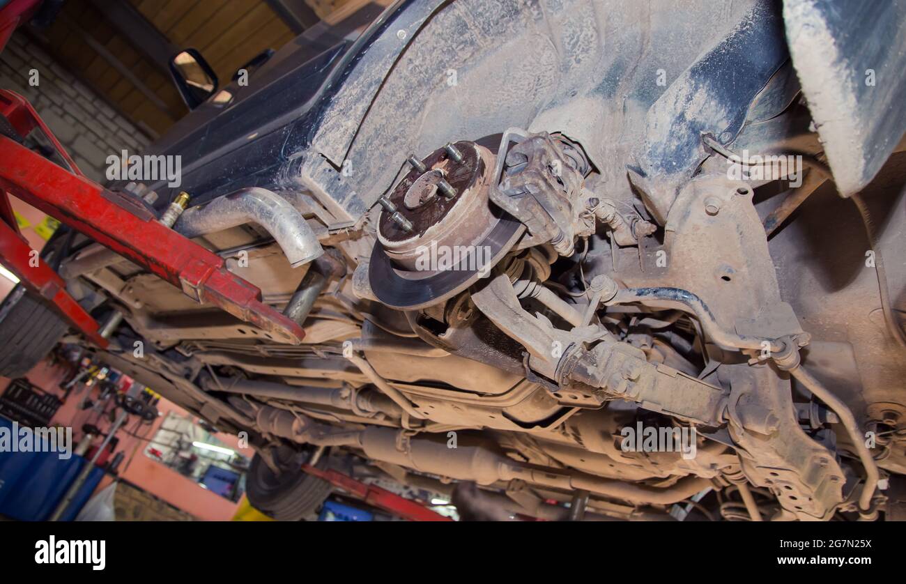 Bottom view of the undercarriage of an old car on a lift. In the garage ...