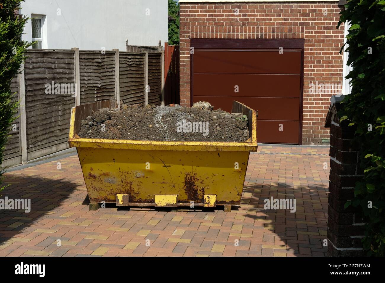 A skip full of soil on a driveway Stock Photo - Alamy