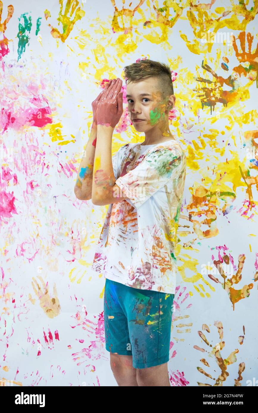Portrait of a cute happy boy painting and having fun. He is showing his ...