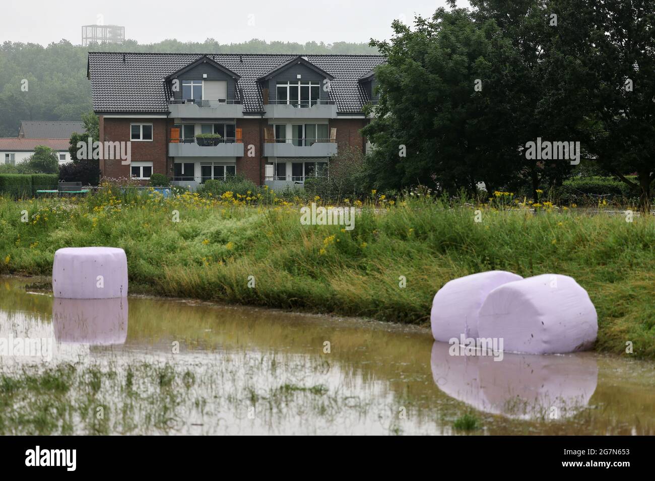 Inden, Germany. 15th July, 2021. Straw bales float in the water of the ...