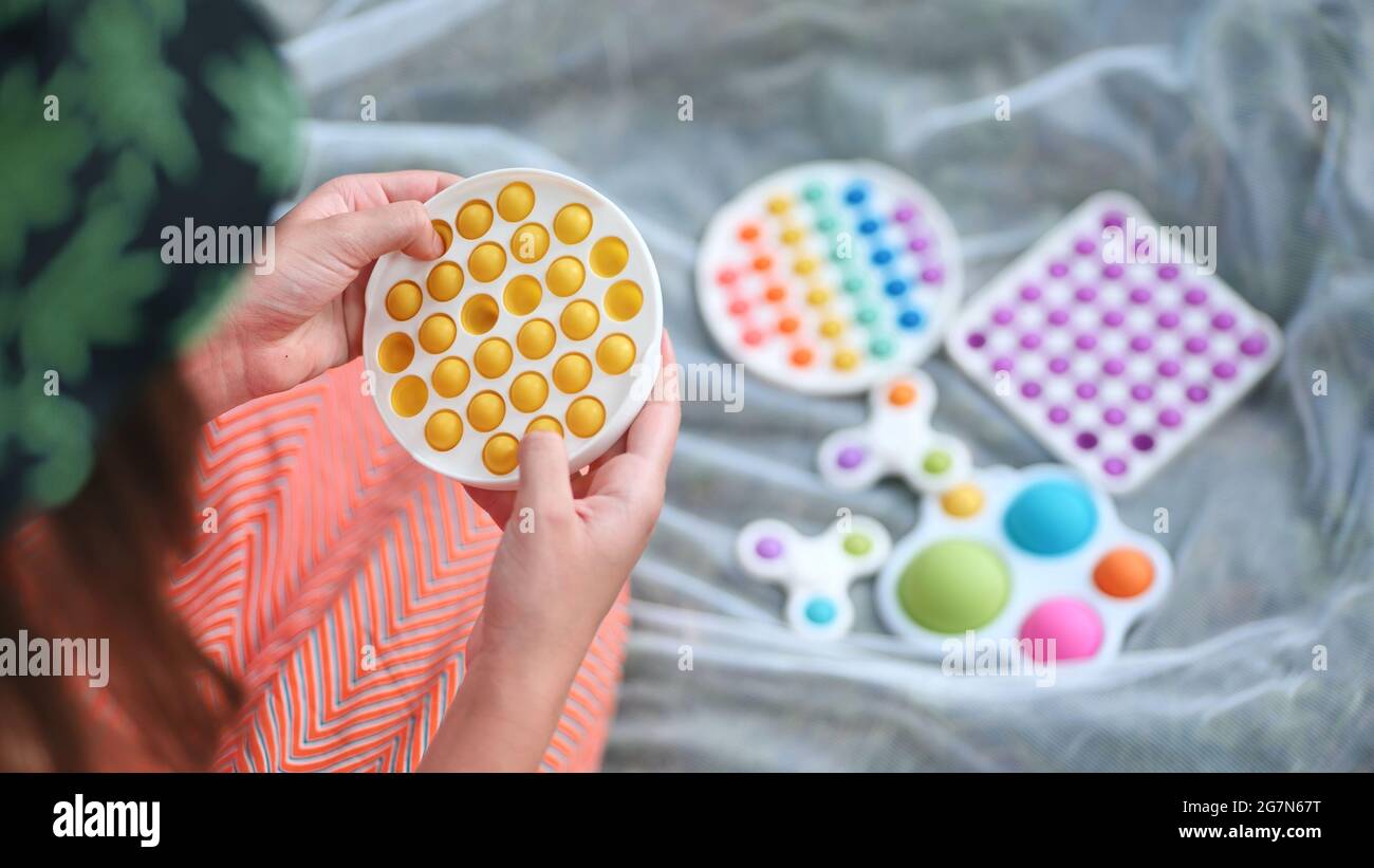 Teen girl plays with anti-stress toys popit and simple dimple in the ...