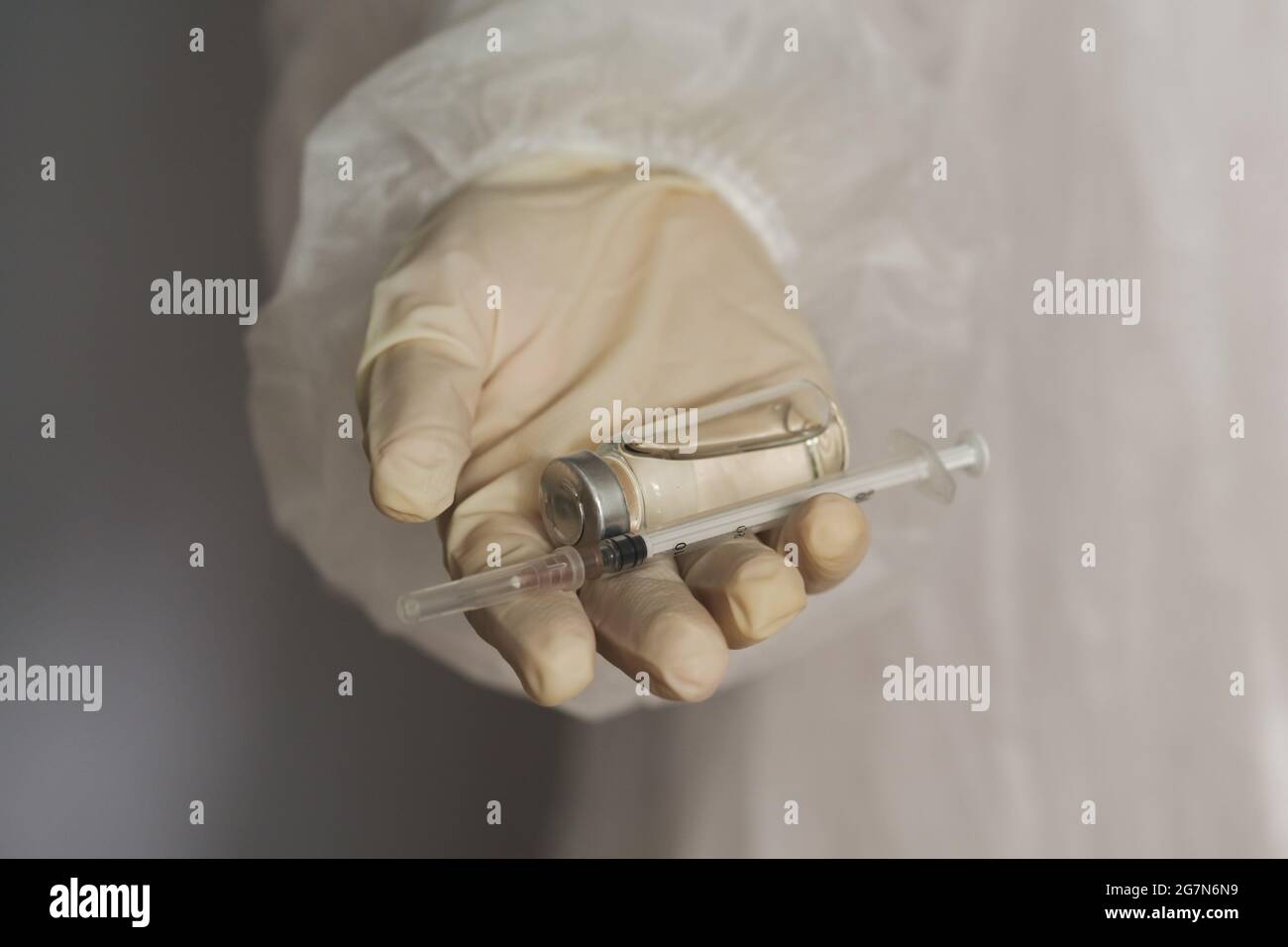 A hand holds a syringe and a vial of medicines for injection, infusion ...
