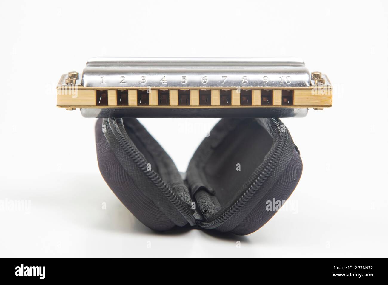 The harmonica lies on a case on a white background. Classical musical ...