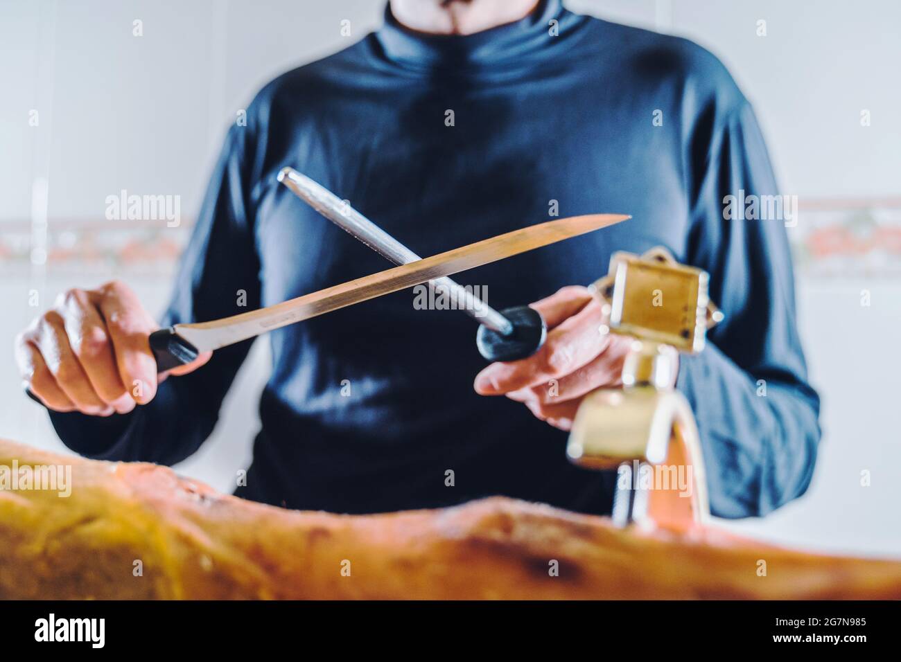 Anonymous person sharpening ham knife before cutting ham. Very well ...