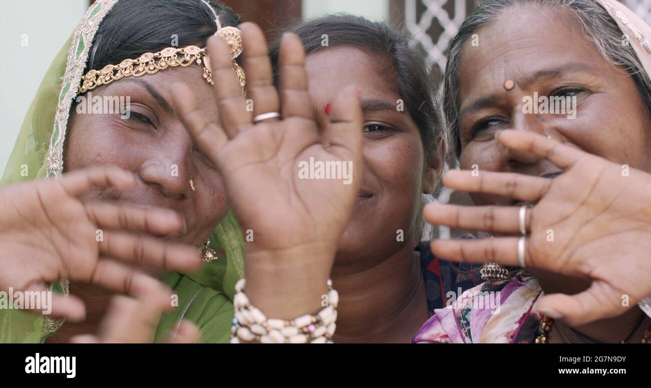 Three beautiful Indian women in traditional costumes waving goodbye ...