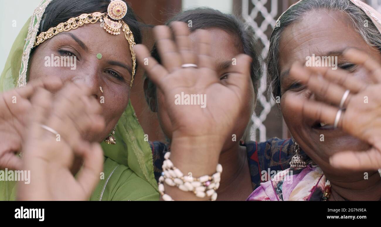 Three beautiful Indian women in traditional costumes waving goodbye ...