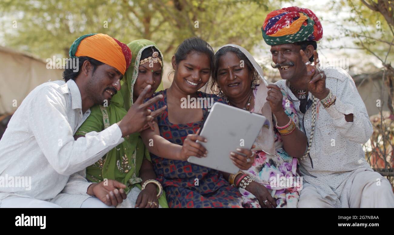 Group of indian people showing a v-sign in front of a tablet outdoors ...