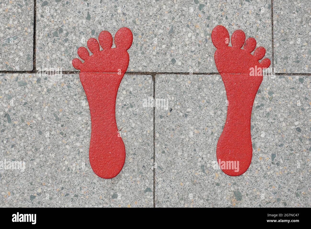 Top view of a foot-shaped red sign on a sidewalk near gargoyle ...