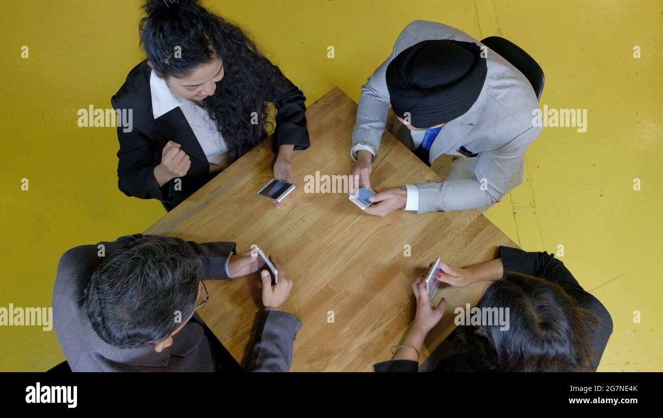 Group of Indian people sitting around the table with their phones in ...