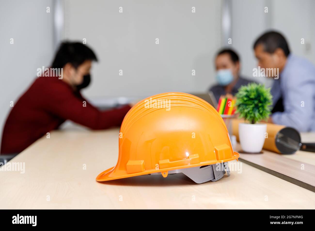 Close up image of a helmet on the desk with architects wearing ...